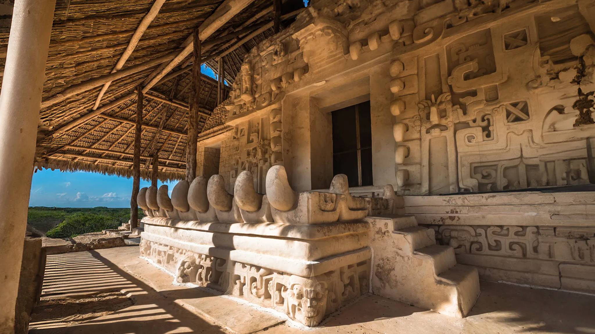 Detailed stone carvings at the Acropolis of Ek Balam, under a thatched ...