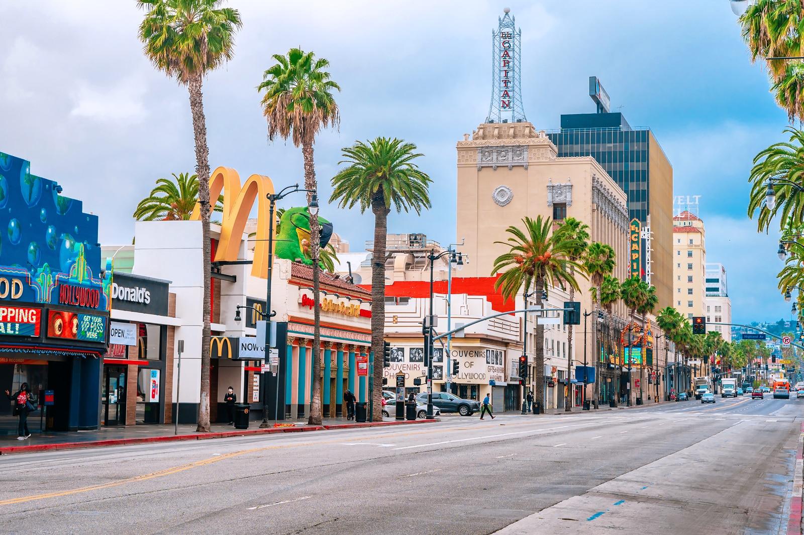 A street in Los Angeles, lined with palm trees and colorful storefronts.