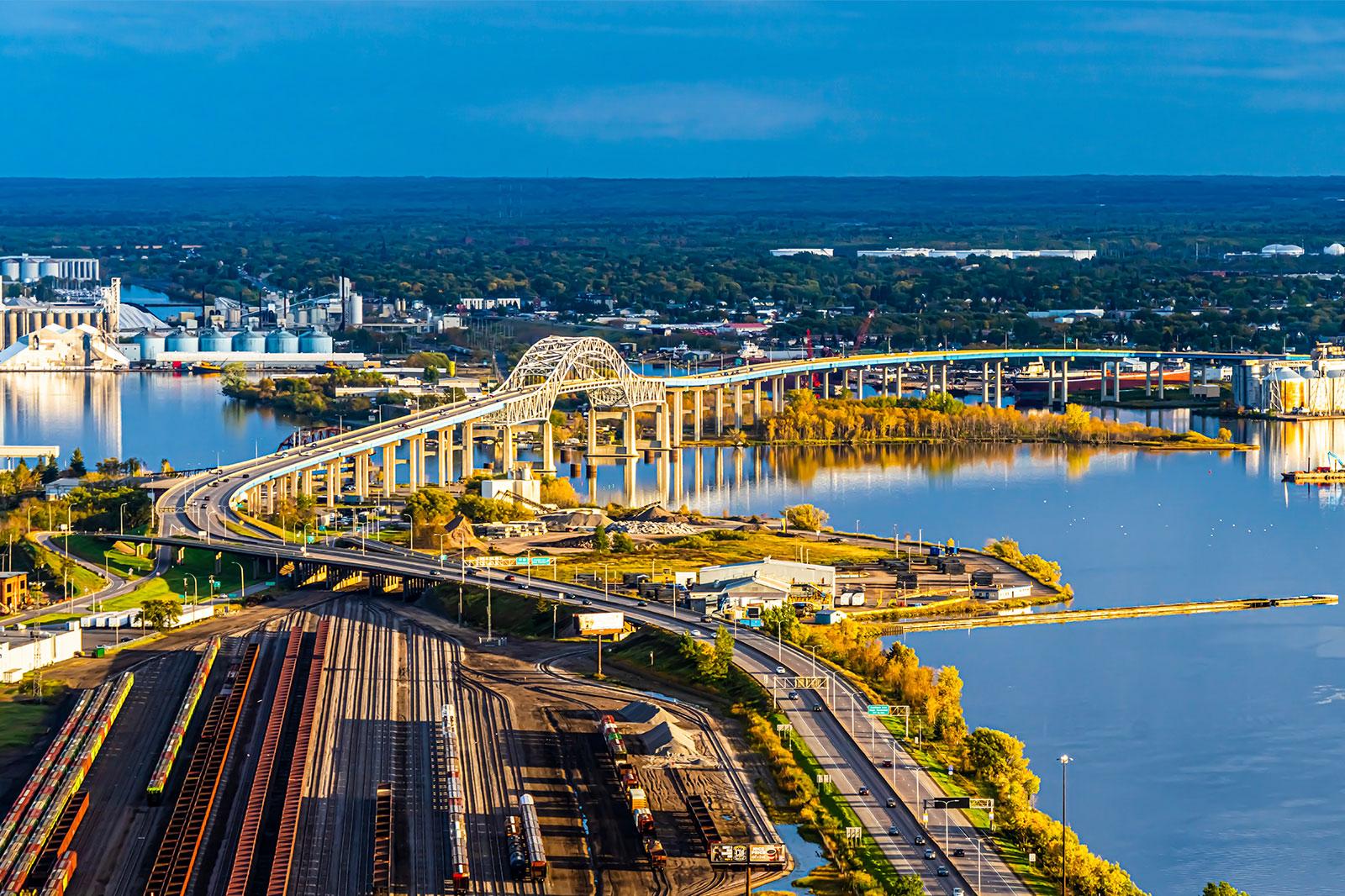 A bridge over a industrial city and water.