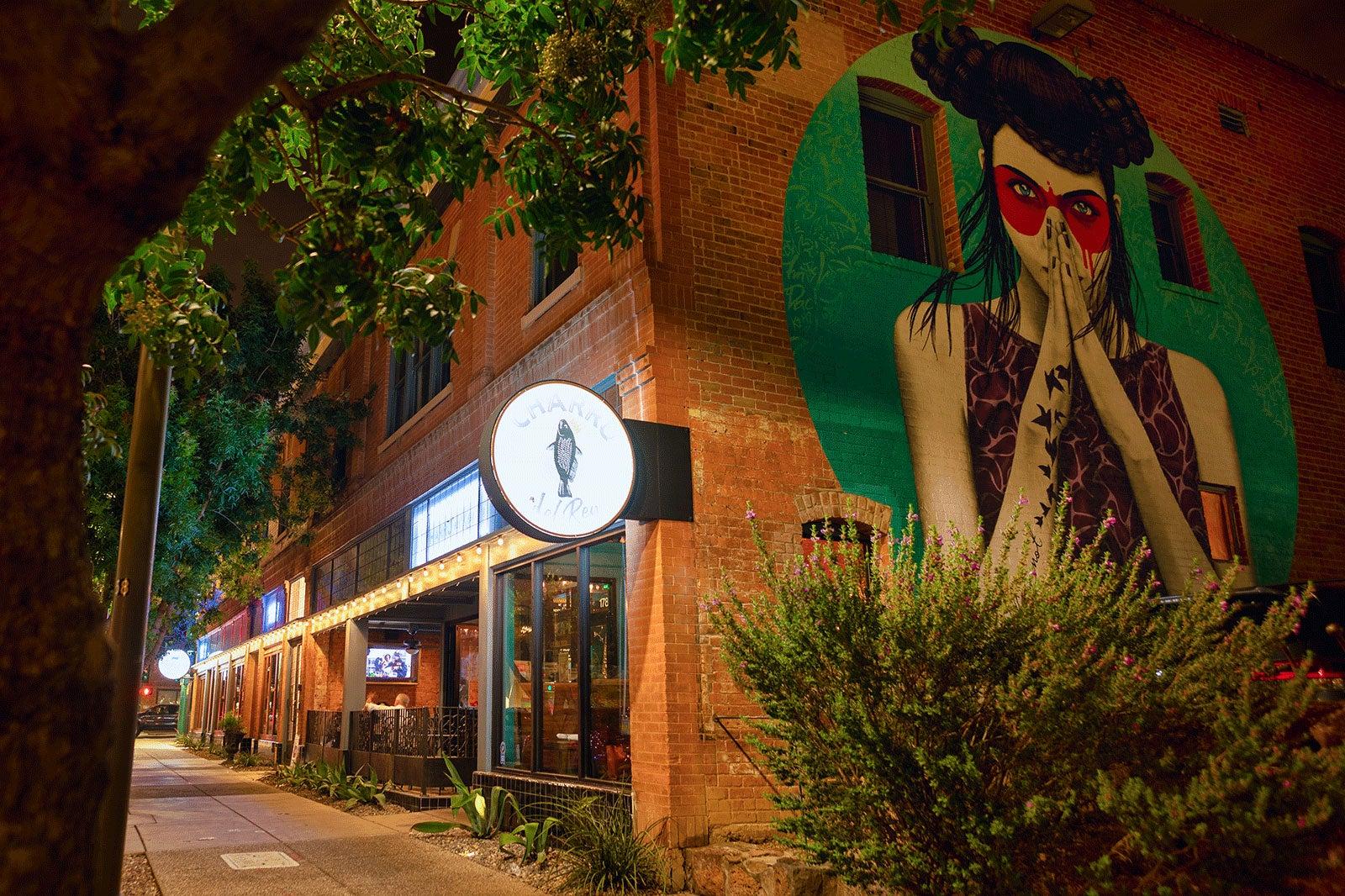 Restaurant with a mural on the wall in Tucson, AZ at night.
