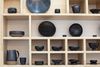 A black pottery dishes and cups on wooden shelves.