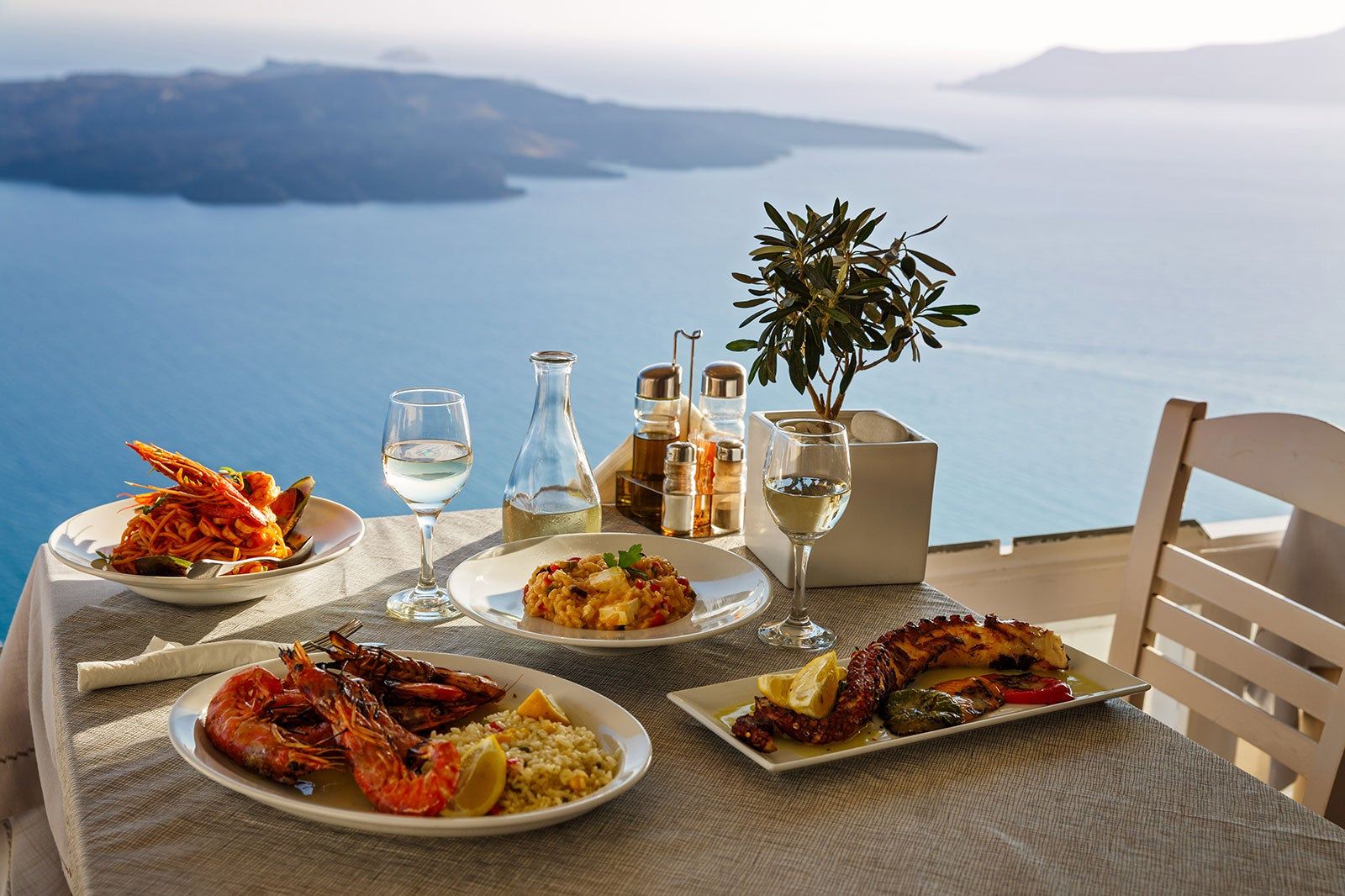 Plates of seafood on a table overlooking the water. 