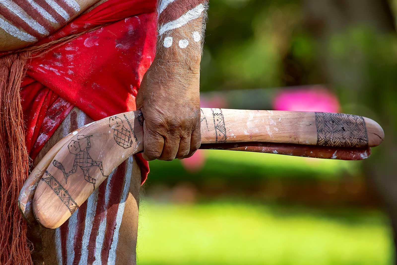 An Aboriginal Australian holding two boomerangs.