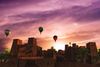 Hot air balloons in the sky over a traditional Moroccan building.