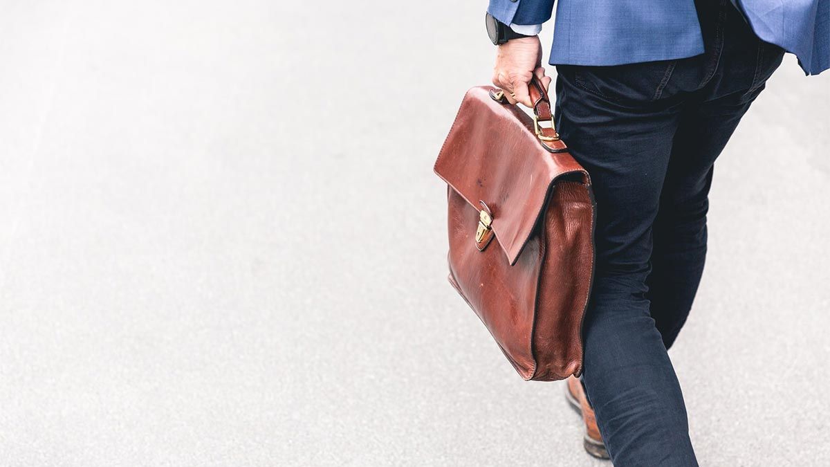 Salesperson walking away in blue suit with brown leather briefcase
